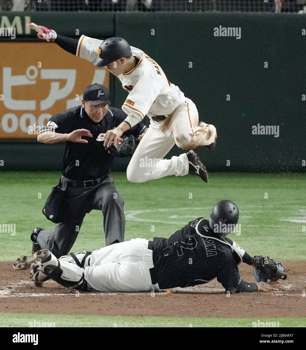 The Yomiuri Giants' Raito Nakayama (top) leaps after scoring on a ...