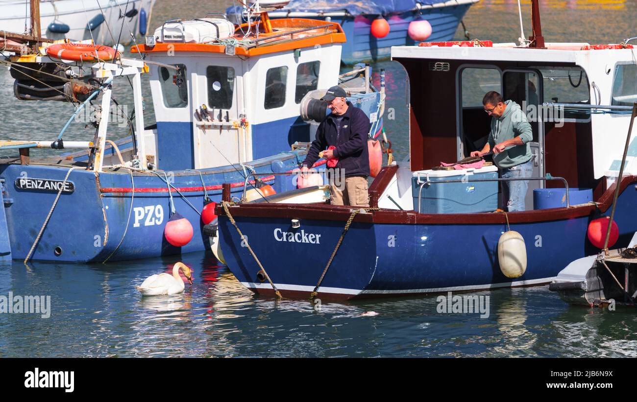 Boat life in a Cornish fishing harbour: Two fishermen at the stern of ...