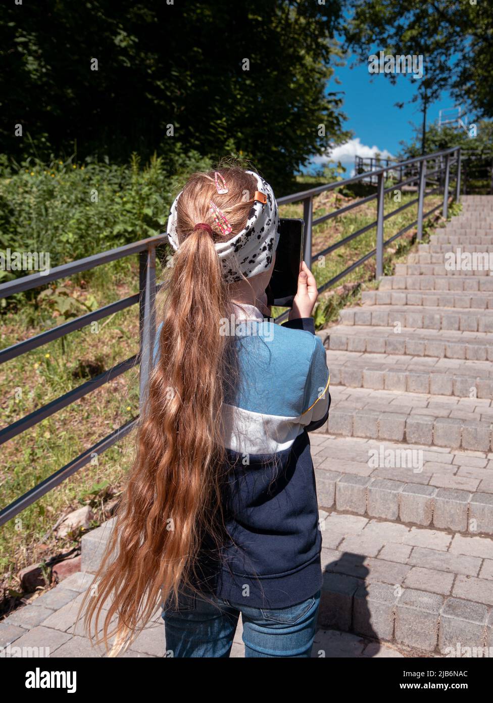 Adorable child girl with long hair chatting in social media smartphone talking on video call ...