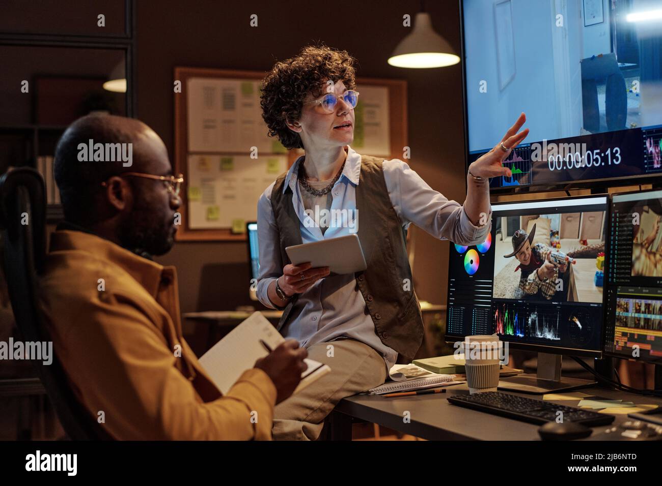 Young project manager pointing at screen and explaining shooting plot ...