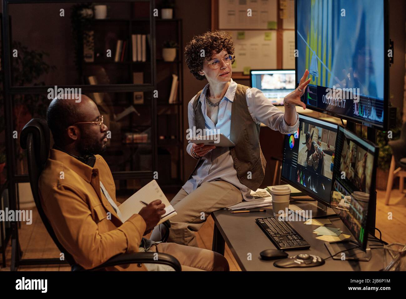 Young project manager pointing at big screen and explaining the idea of ...