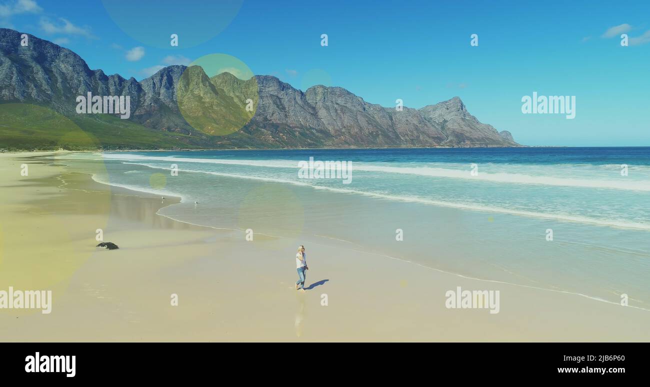 Multiple light spots floating against caucasian woman walking at the ...