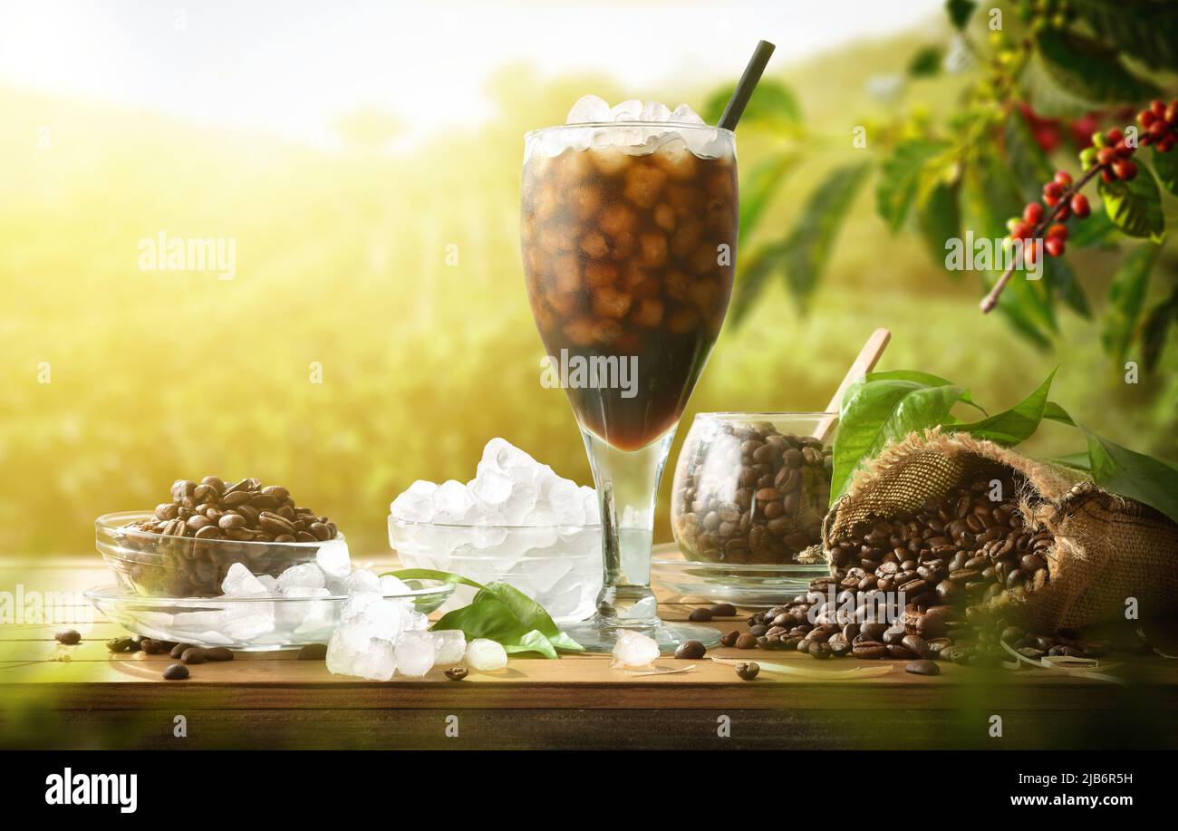 Iced coffee on wooden table with crushed ice and coffee beans around it ...