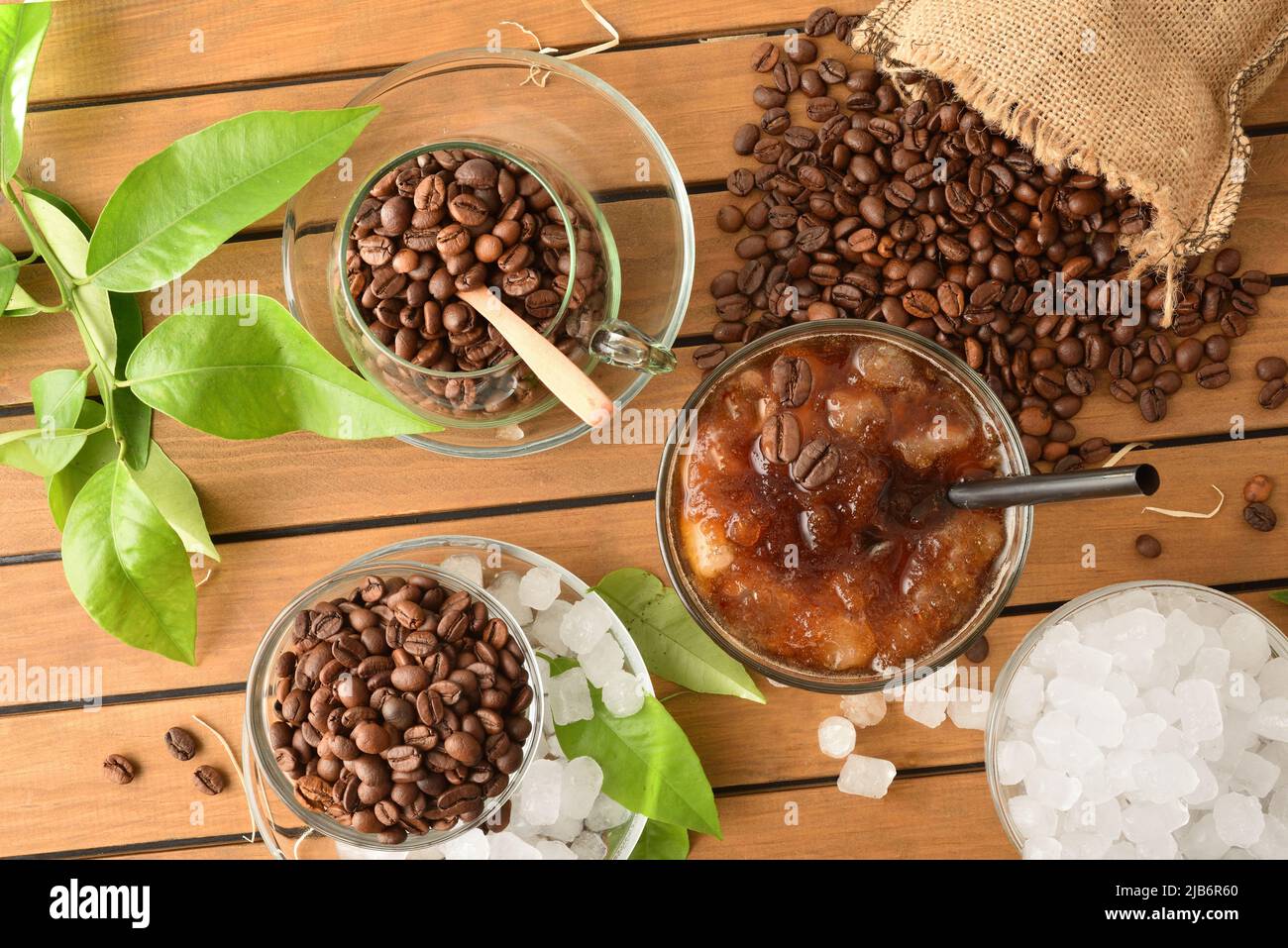 Iced coffee on wooden table with crushed ice and coffee beans around it ...