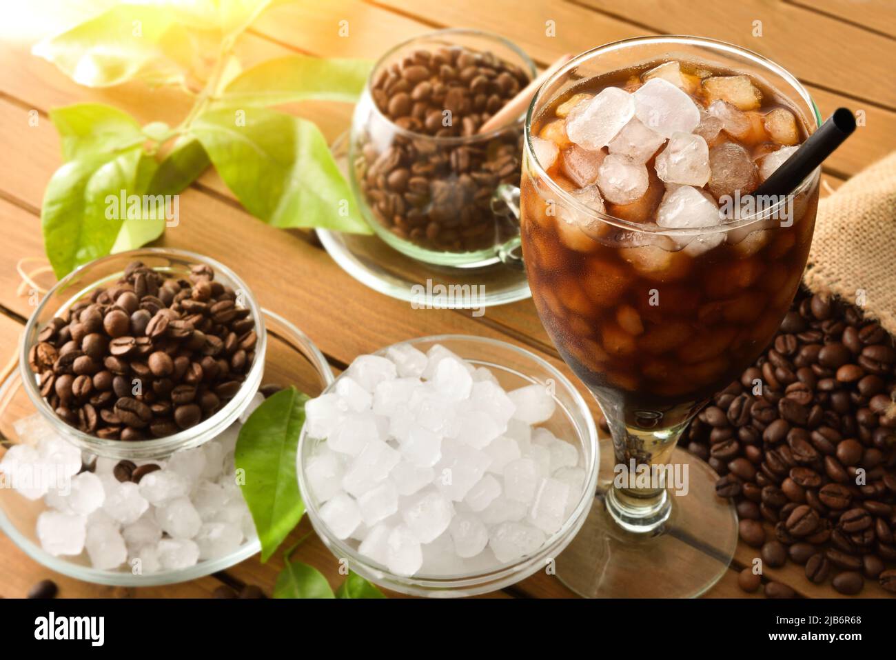 Iced coffee on wooden table with crushed ice and coffee beans around it ...