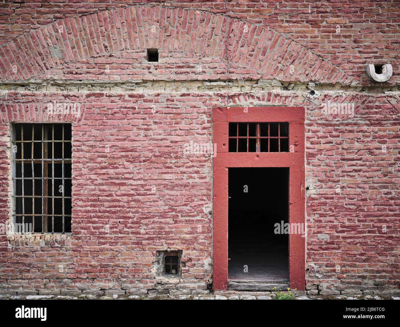 Facade of a brick house with a door and a barred window in an old ...
