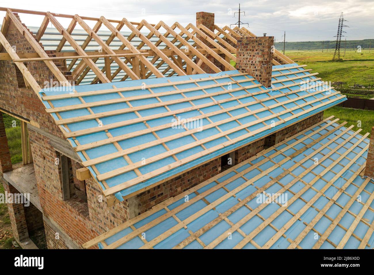 Aerial view of a brick house with wooden roof frame under construction ...