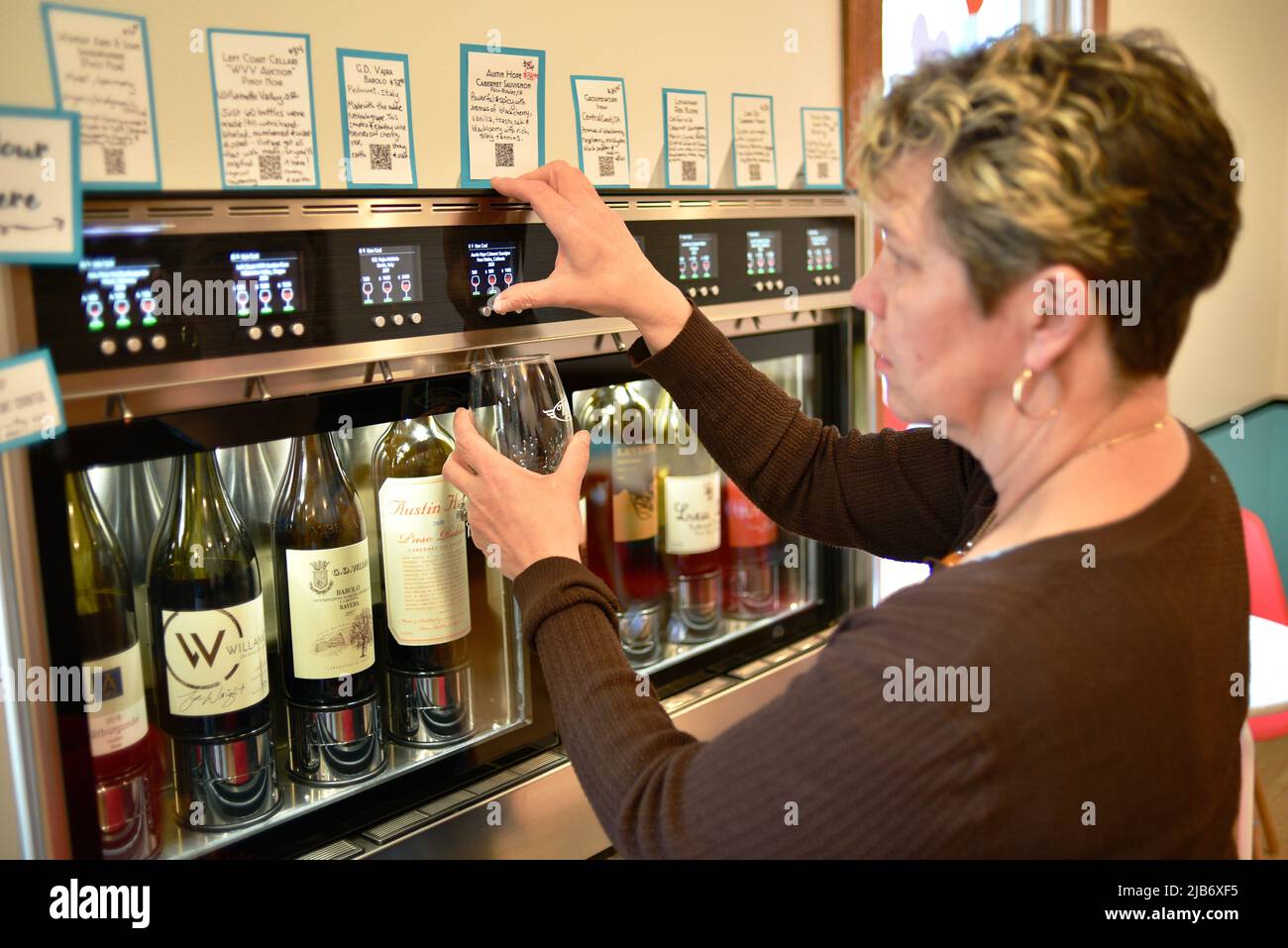 Woman customer using automated wine dispensing system, Wine-E-Motion ...