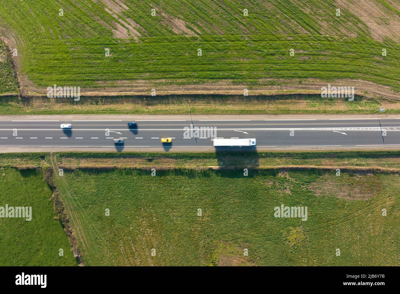 Aerial view of intercity road between green agricultural fields with ...