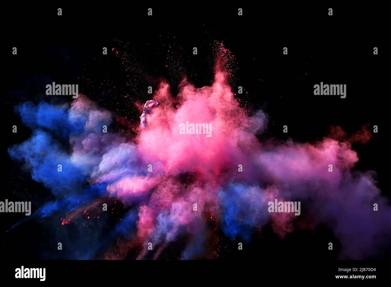 Various multicolored forms of powder paint explode in front of a black ...
