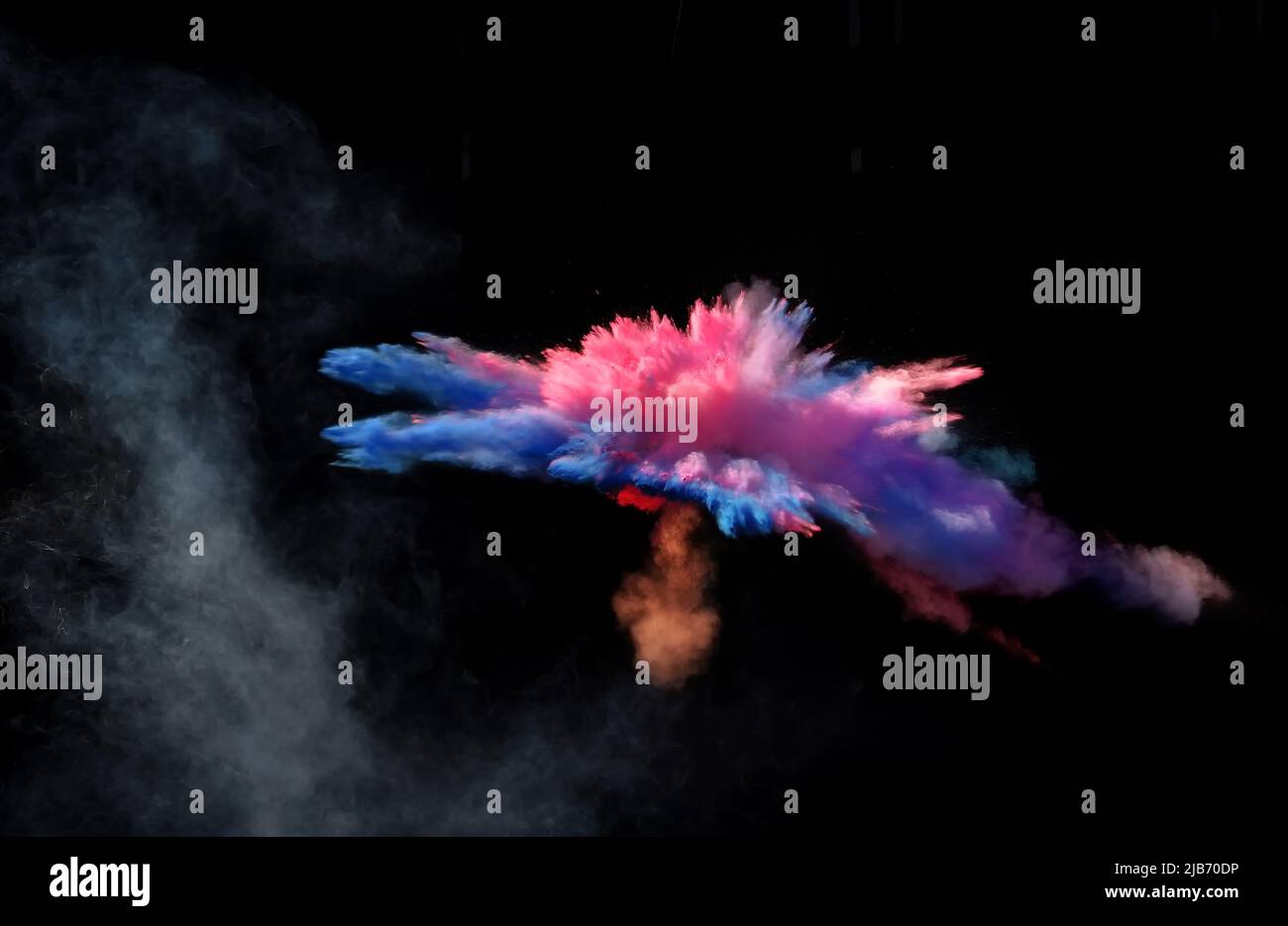 Various multicolored forms of powder paint explode in front of a black ...
