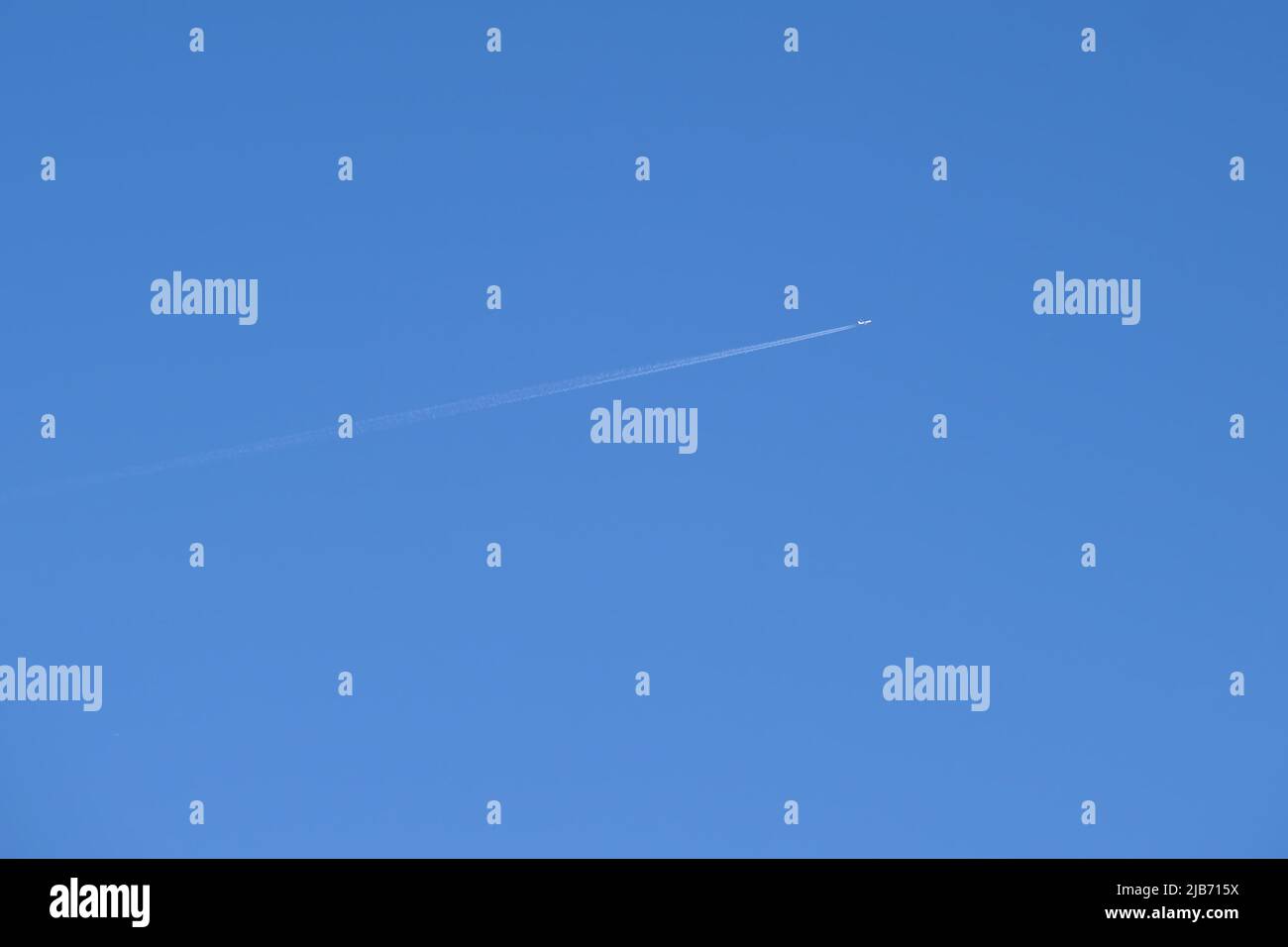 Distant passenger jet plane flying on high altitude on clear blue sky ...