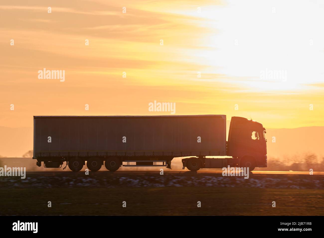 Semi-truck with cargo trailer driving on highway hauling goods in evening. Delivery ...