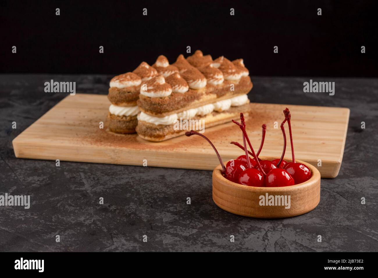 Dessert Tiramisu cake on a tray on a dark background in a coffee shop ...