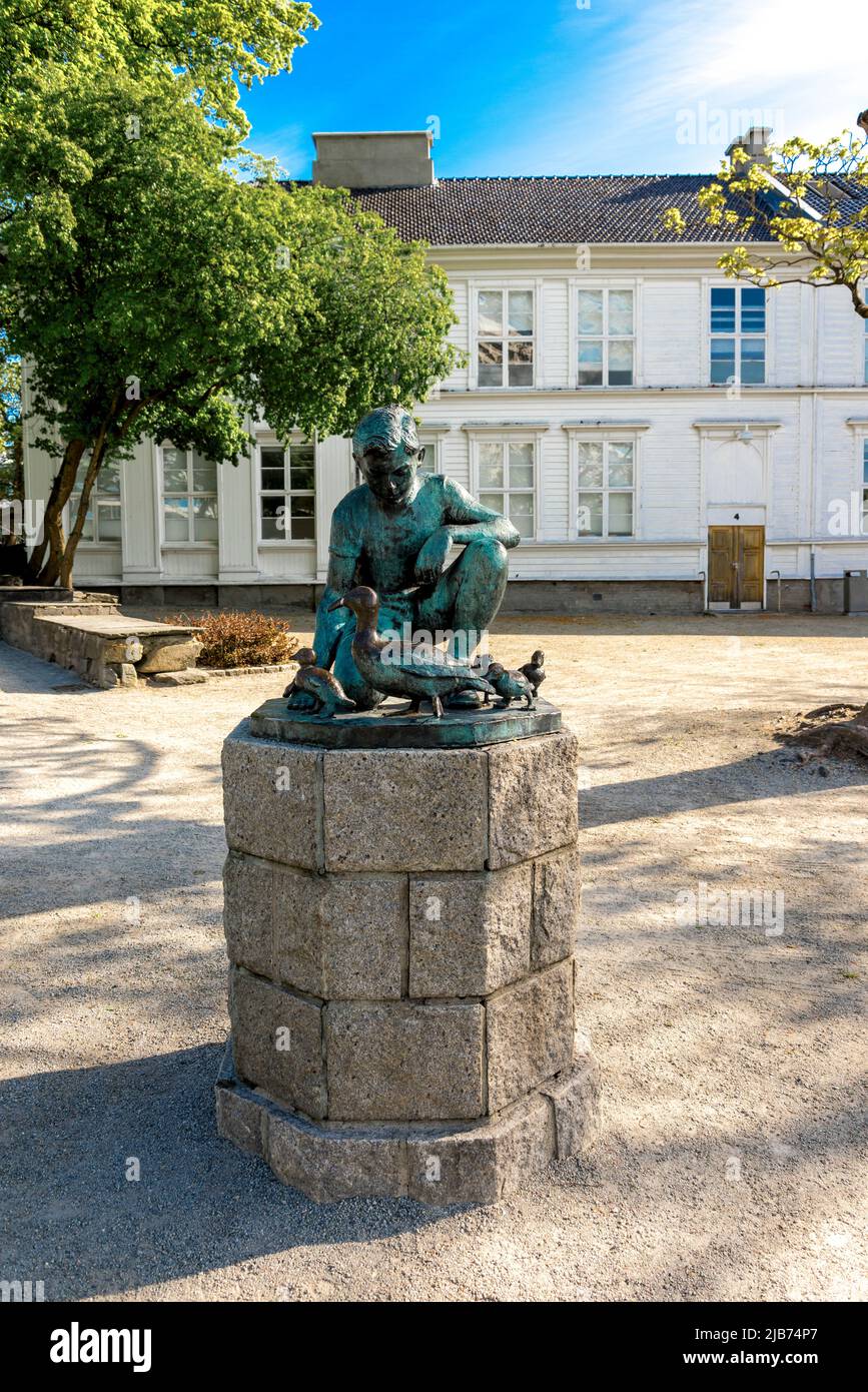 A small bronze statue of a sitting boy with a duck family in Stavanger ...