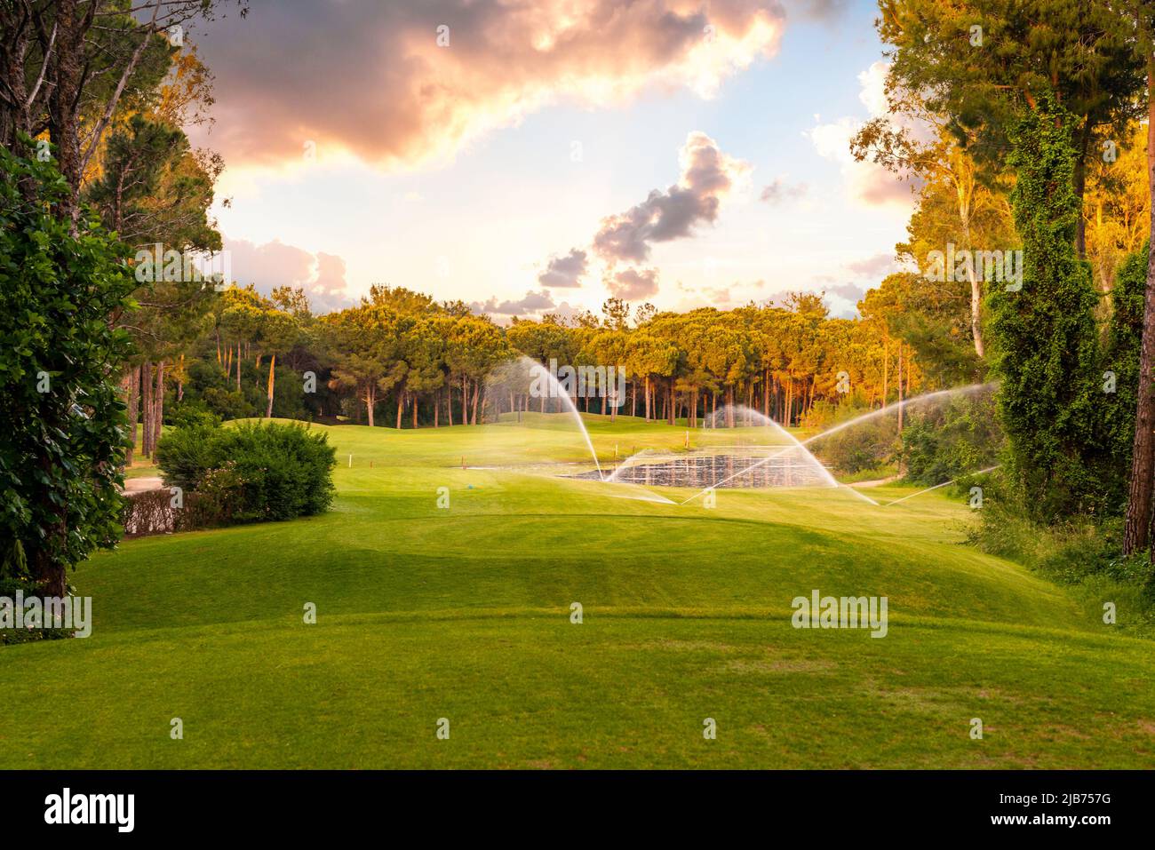 Watering grass in golf course at sunset with beautiful sky. Scenic ...
