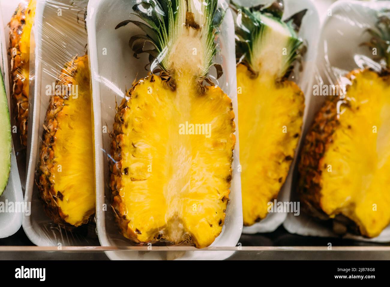 Opened fresh pineapple wrapped in plastic on display at a supermarket ...