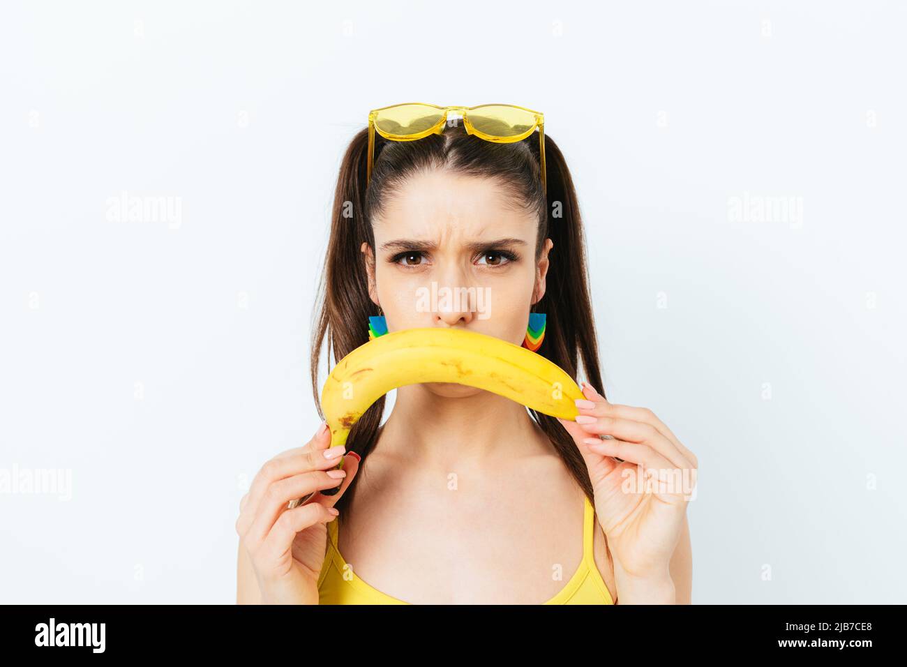 Young woman wearing yellow summer top and sunglasses looking angrily at ...