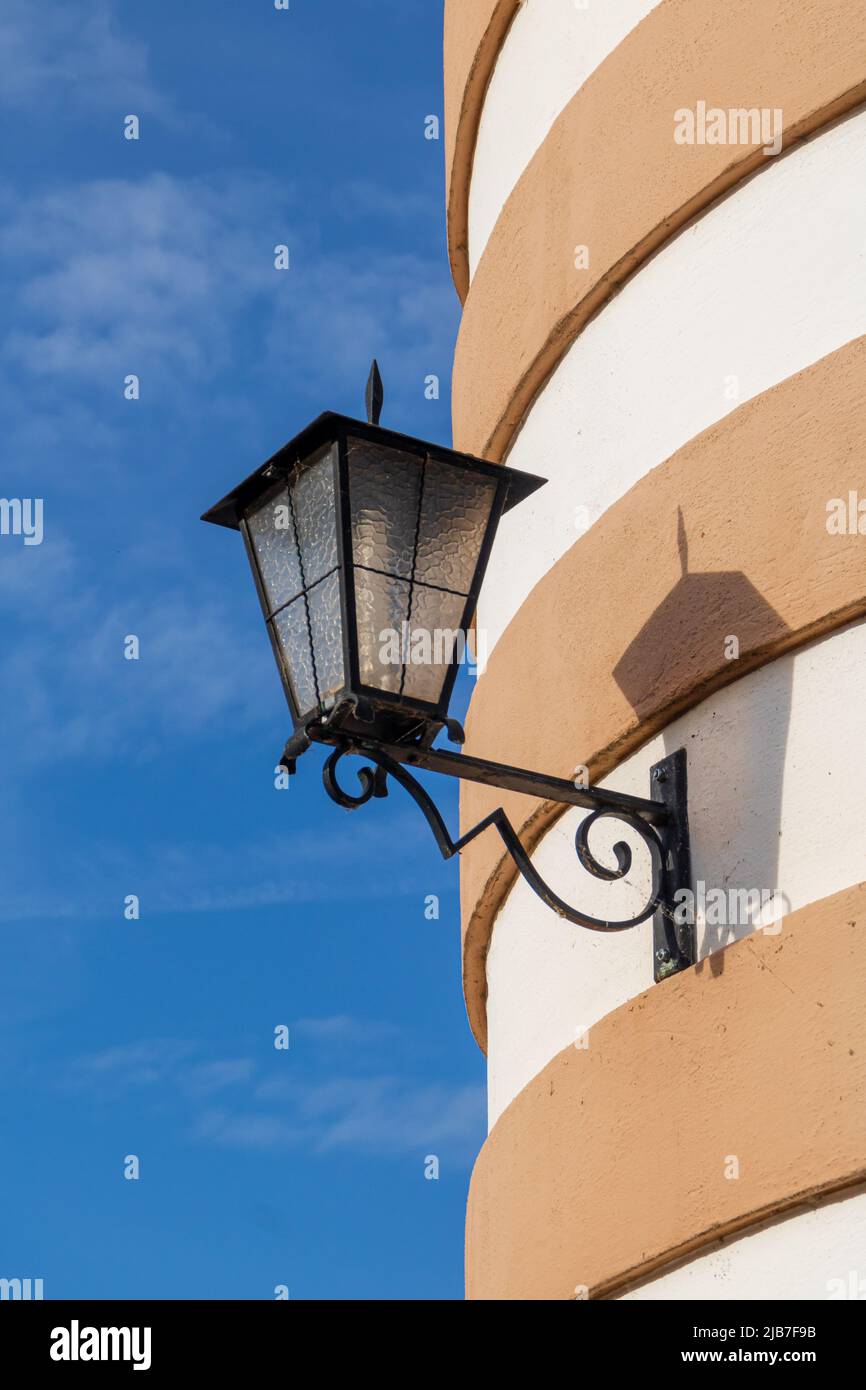 old, ornate iron street lantern hangs hangs on a round tower with ...