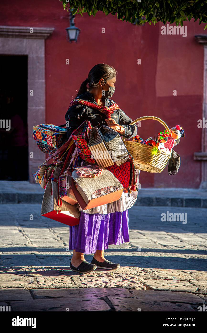 An indigenous woman selling a variety of Mexican related folk art in ...