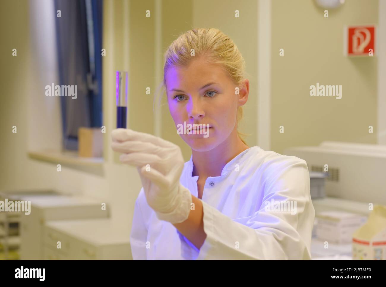 A young student takes up her duties as lab assistant. She wears a white ...