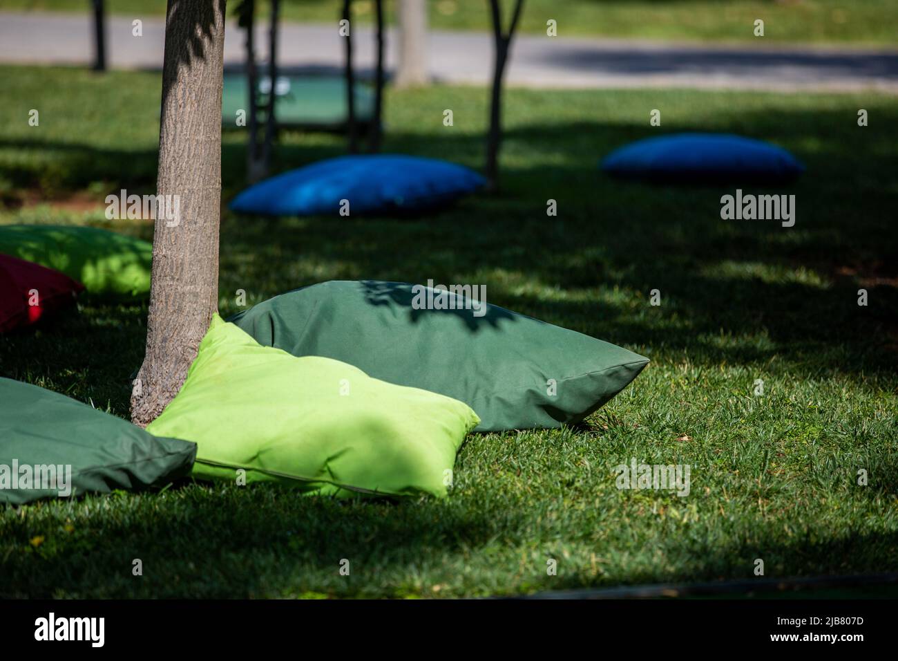 Students sitting on cushions under trees Stock Photo - Alamy