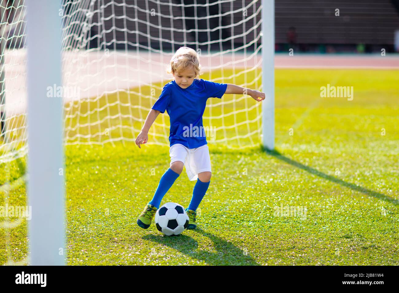 Kids play football on outdoor stadium field. Children score a goal ...
