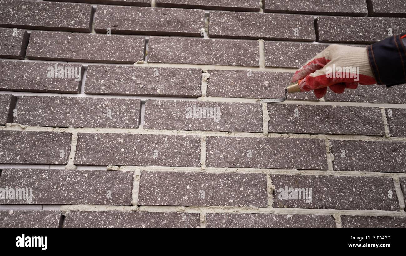 A worker applies mortar to a building's facade. Grouting tiles on the ...