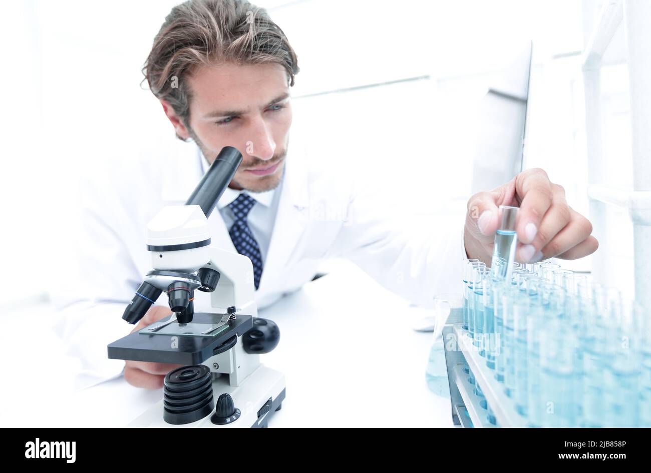 Chemist looking at test-tubes with blue liquids Stock Photo - Alamy