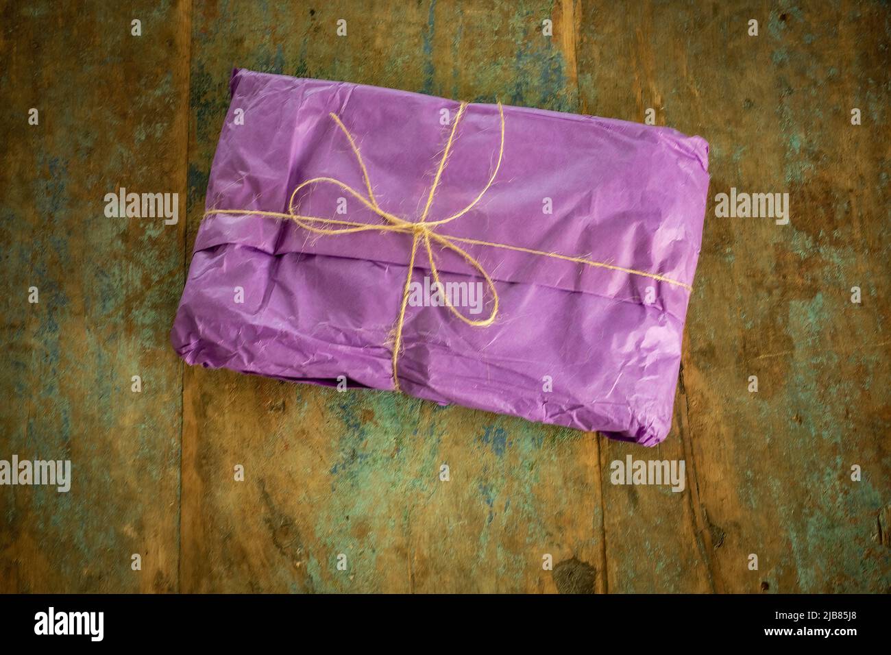 gift wrapped present, wrapped in purple tissue and with a string bow ...