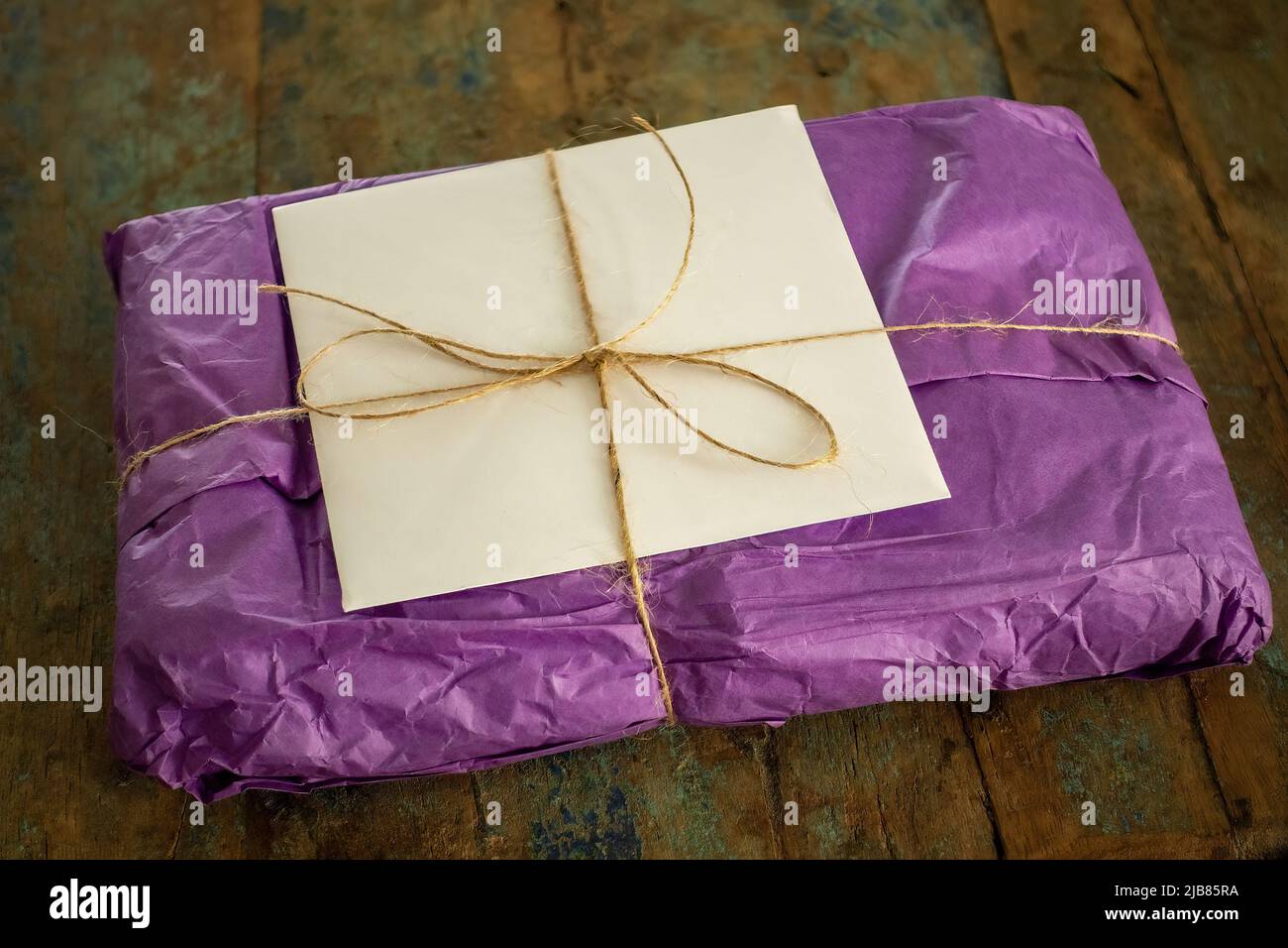 gift wrapped present, wrapped in purple tissue and with a string bow ...