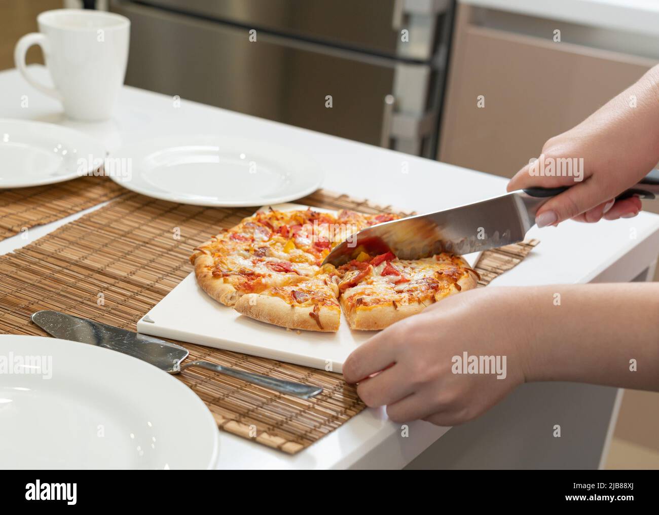 homemade pizza on the table is cut with a kitchen knife Stock Photo - Alamy
