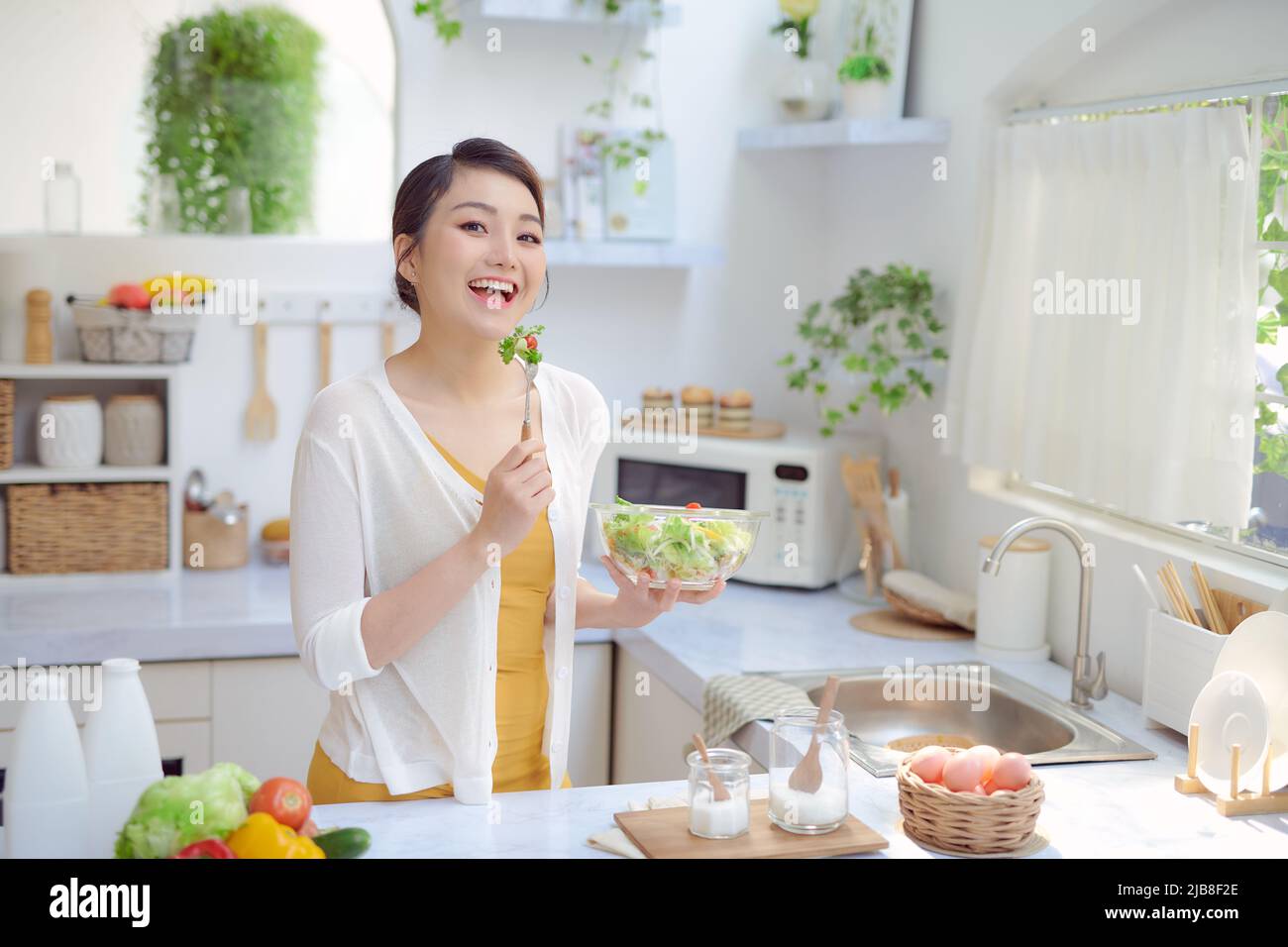 Pretty woman eating a salad in the kitchen Stock Photo - Alamy