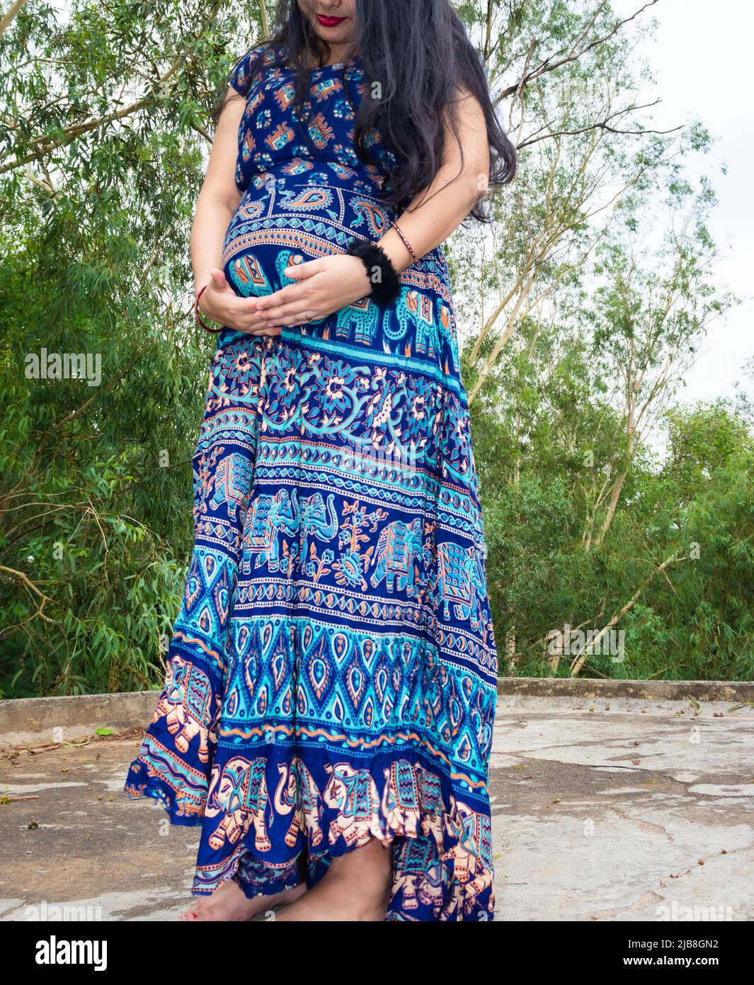 young pregnant women showing her round belly womb with hand from ...