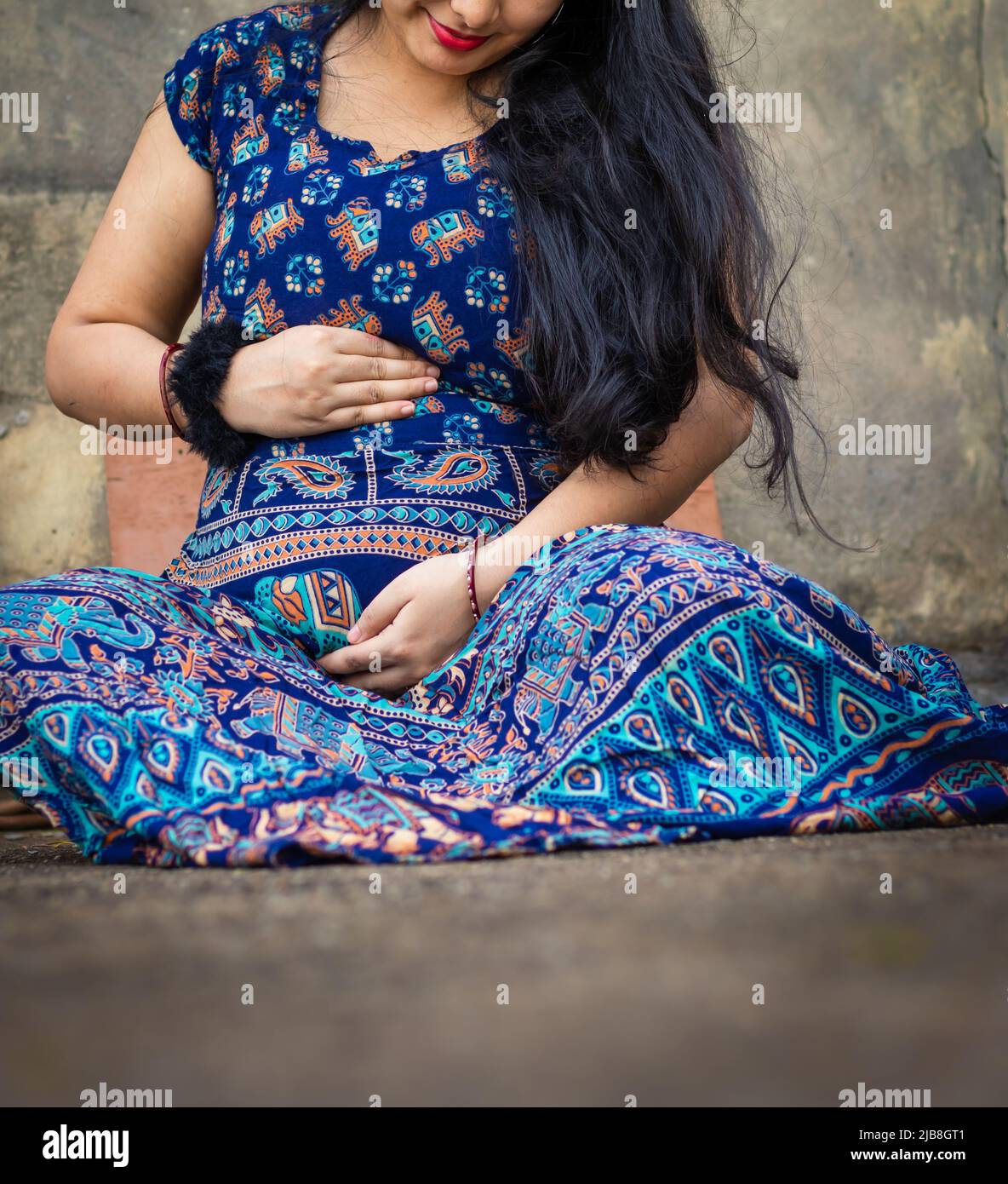 young pregnant women showing her round belly womb with hand from ...