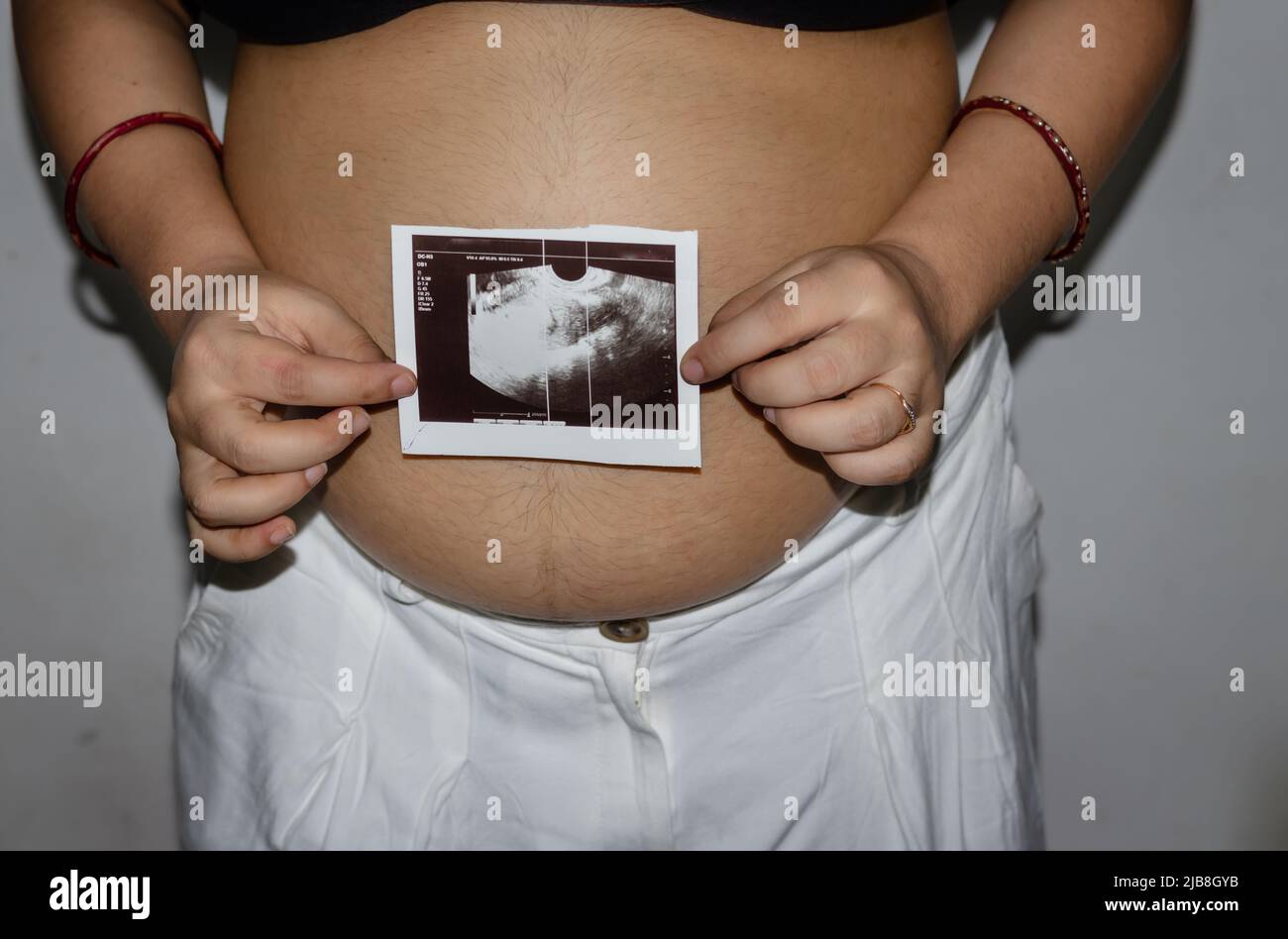 young pregnant women showing her sonogram with round belly womb from ...
