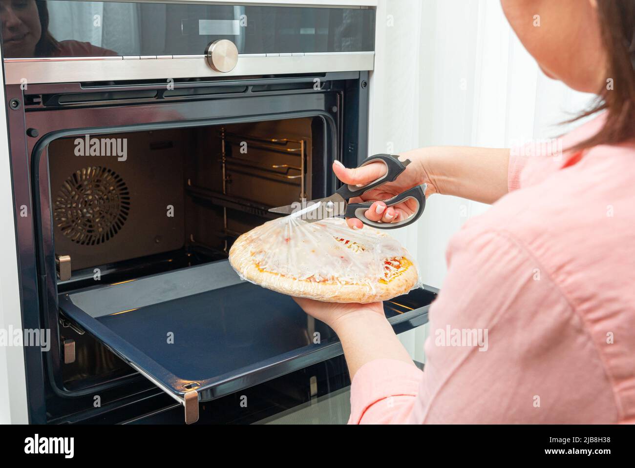 View from the back female hands cutting a package with pizza with ...