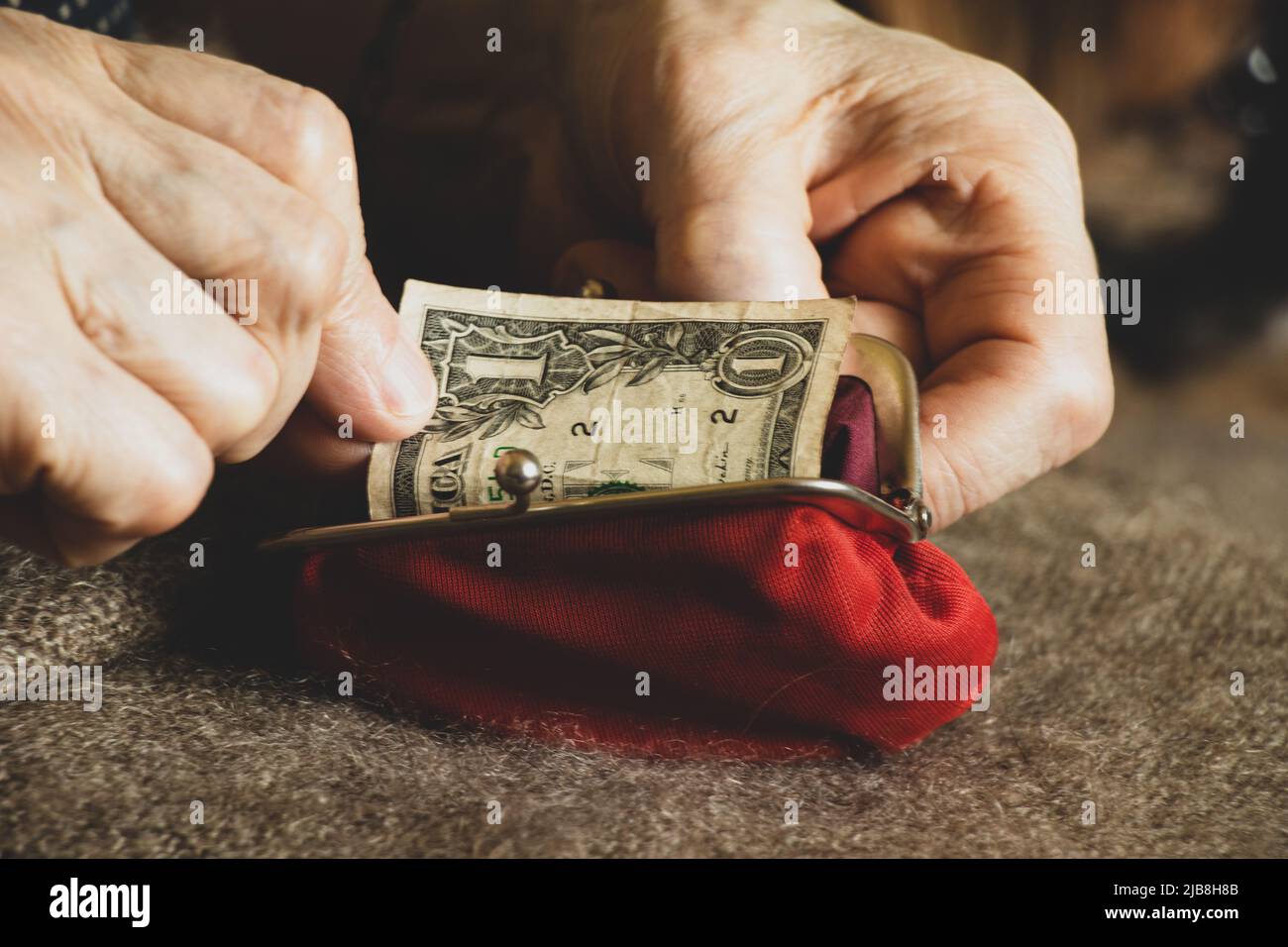 old woman's hands take out a dollar bill from a soft red wallet, money ...