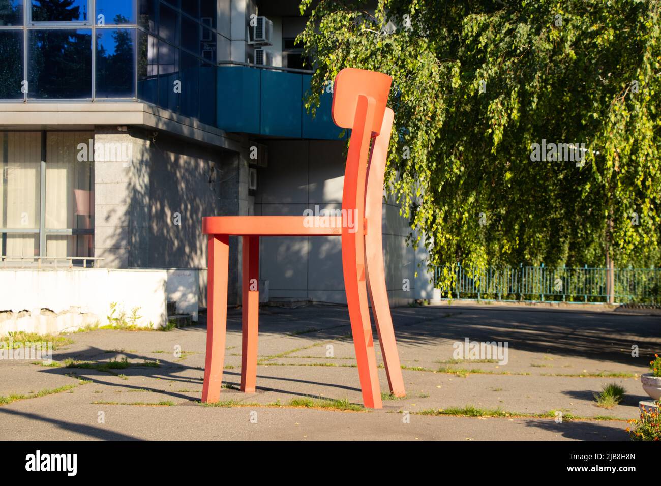 a group of large chairs on the street near the building in the sun ...