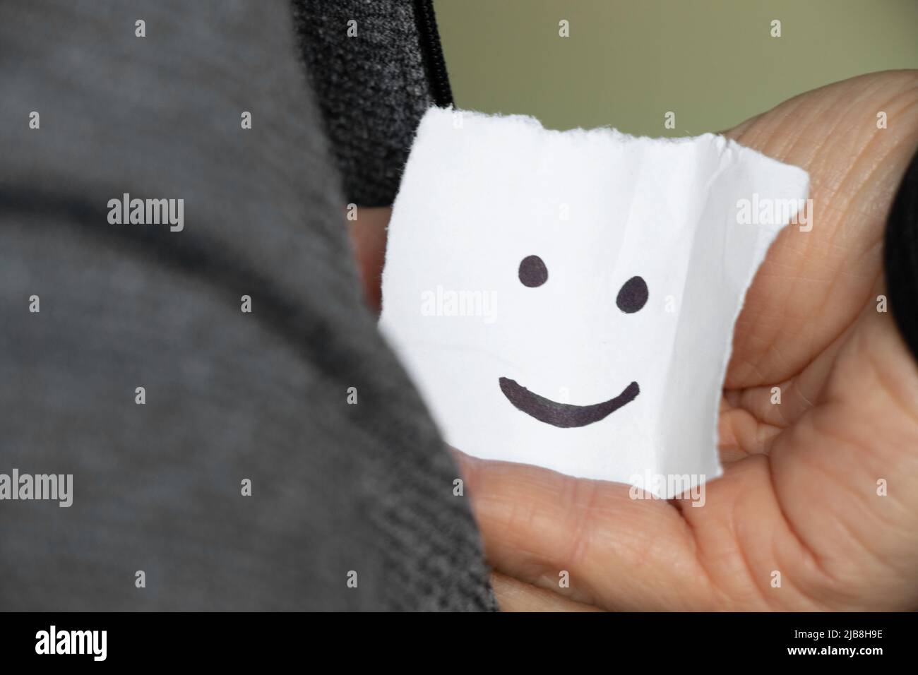 a cheerful emoticon is drawn on a piece of paper in the hands of a ...