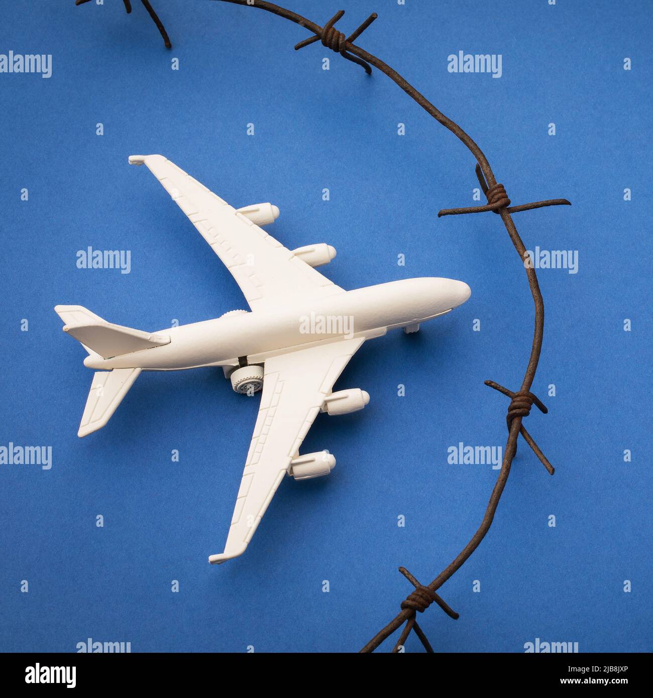 Airplane and barbed wire on a blue background, a concept on the theme ...