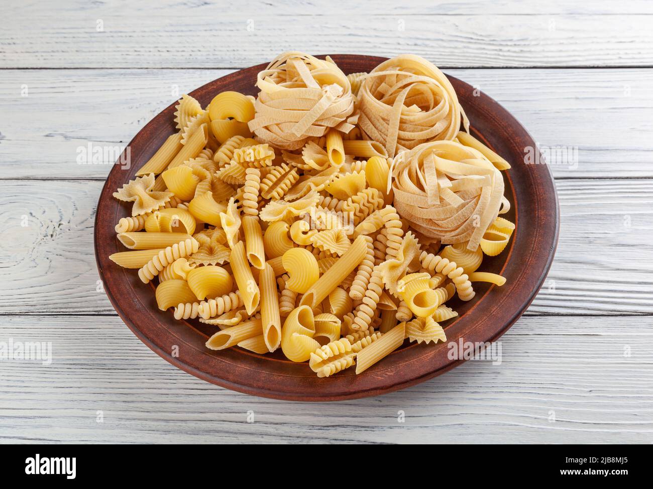 Different types and shapes of Italian pasta in ceramic plate on white ...