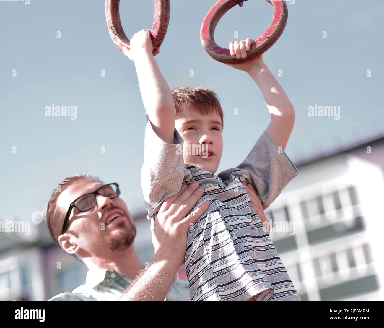 father helps his son to catch up on the bar.the concept of parenting ...