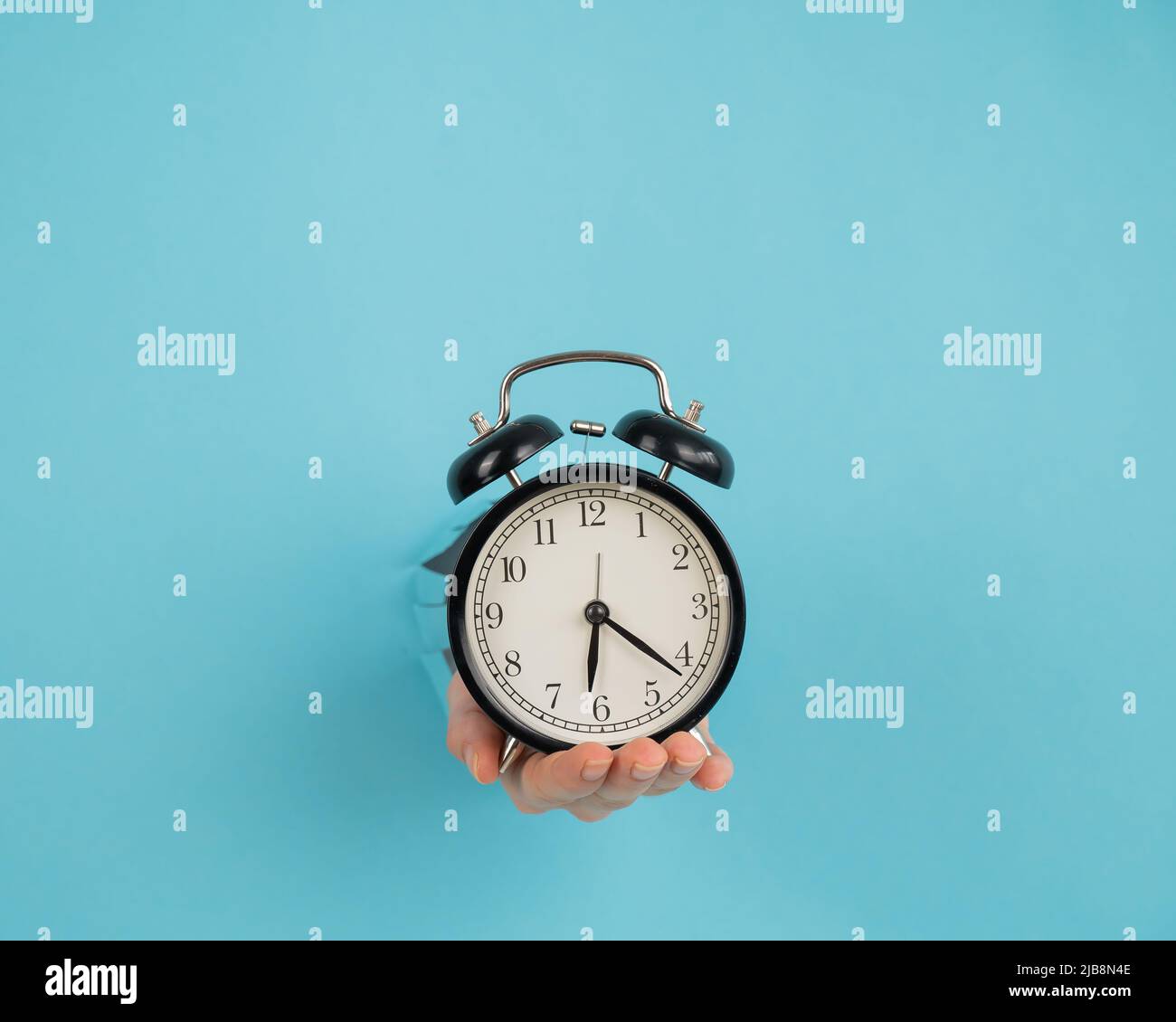 A woman's hand sticks out of a hole in a blue paper background and ...