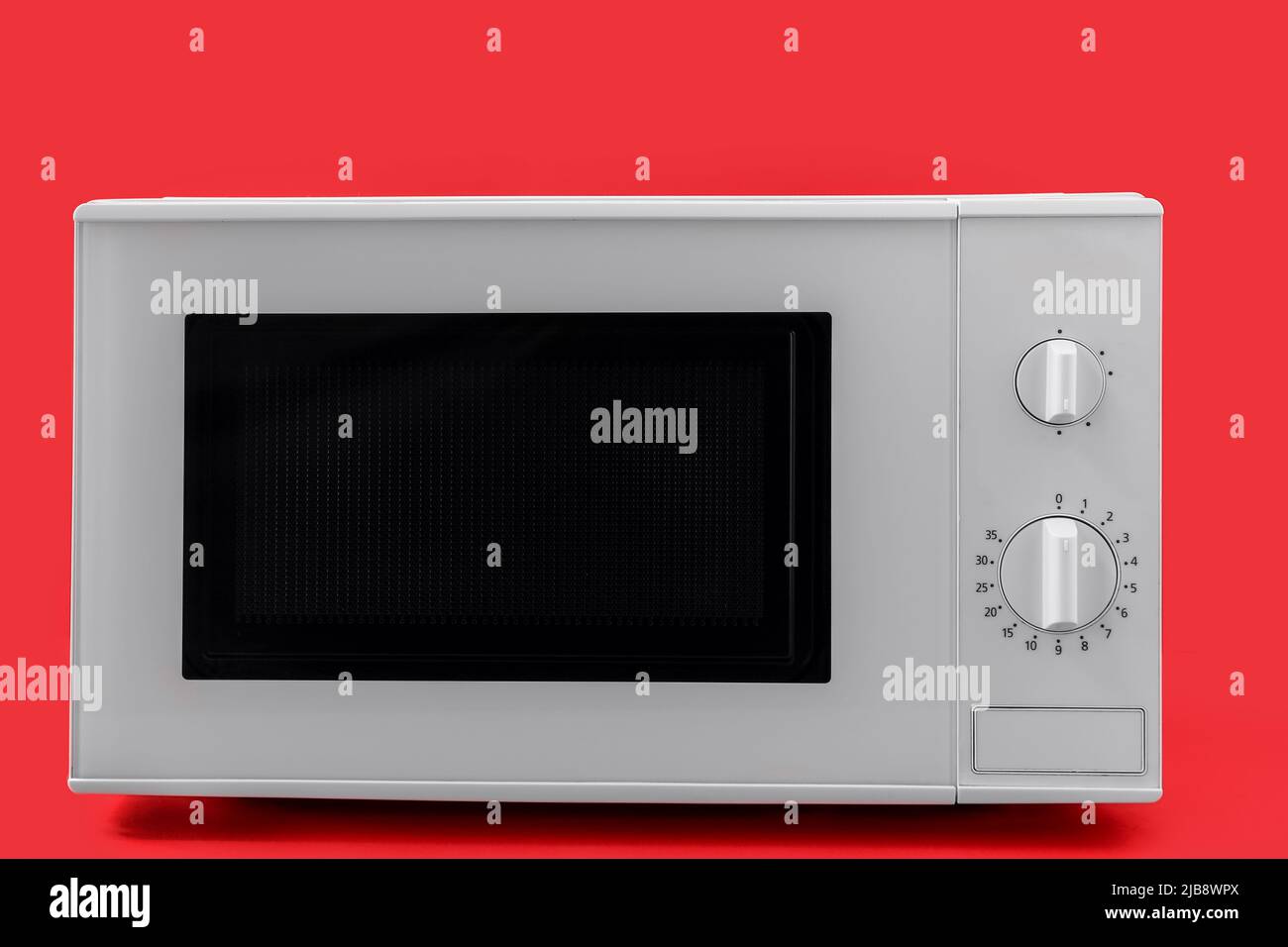 New modern microwave oven on red background Stock Photo - Alamy