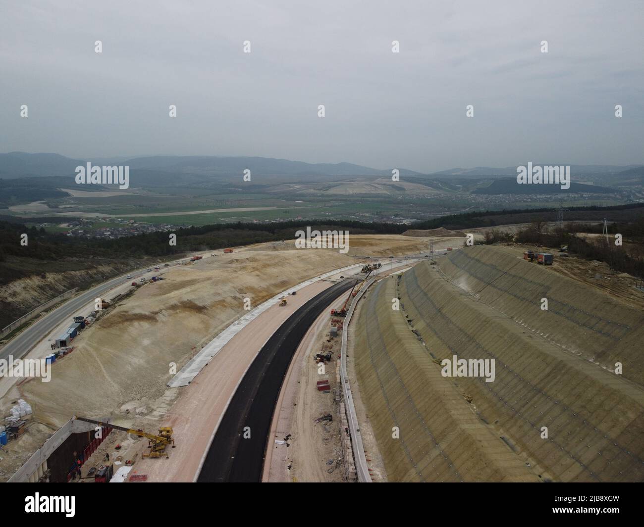 Workers reinforce the slope over the new road. Road construction in ...