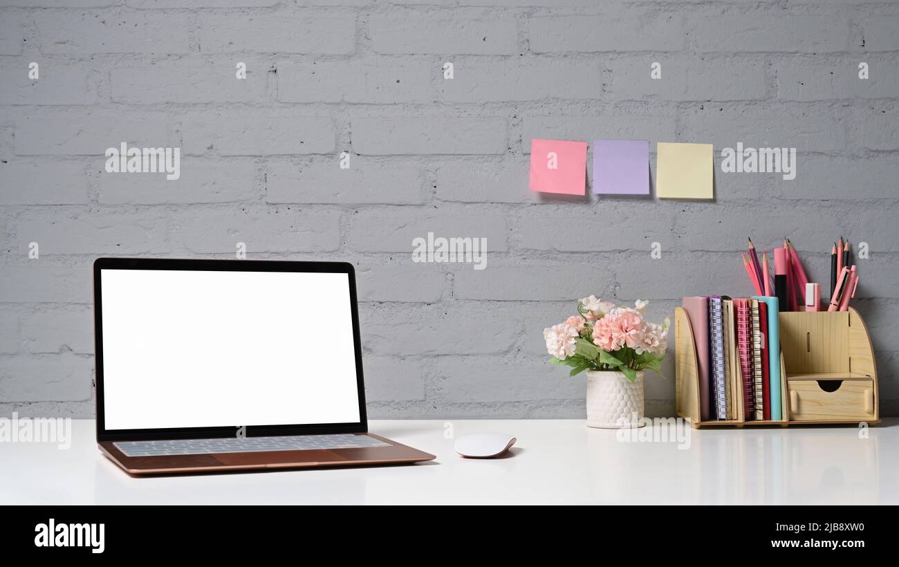 Stylish workplace with computer laptop, flower pot, stationery and ...
