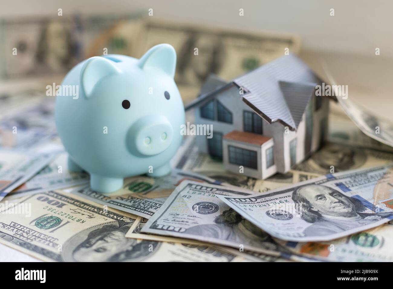 Small paper house and piggy bank on a pile of dollar banknotes, Money ...