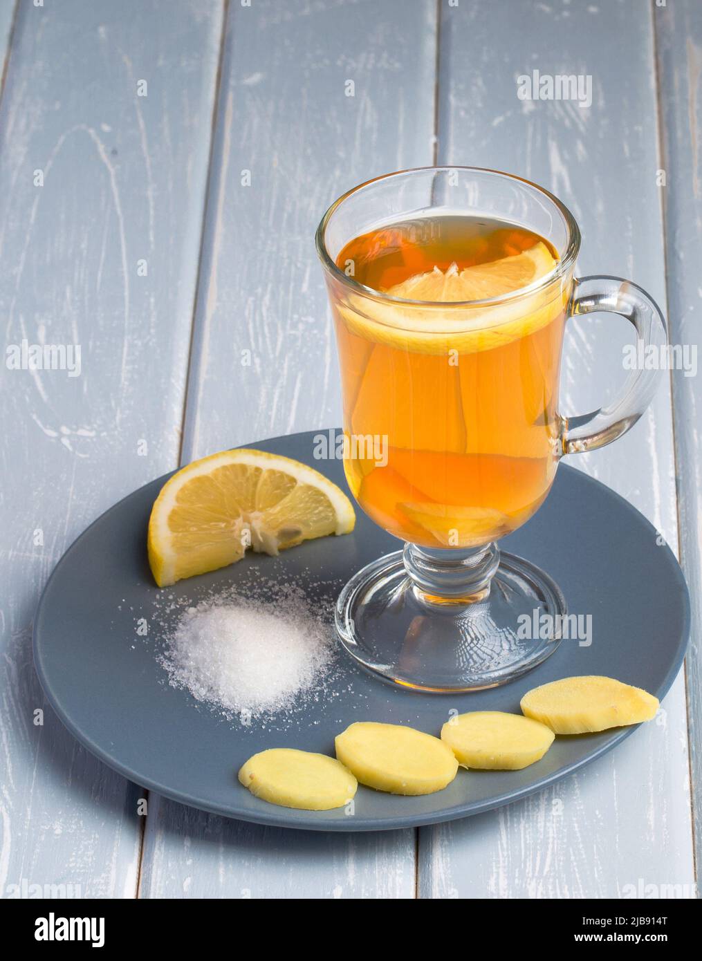 A transparent glass filled with ginger tea with lemon.On a dark wooden ...
