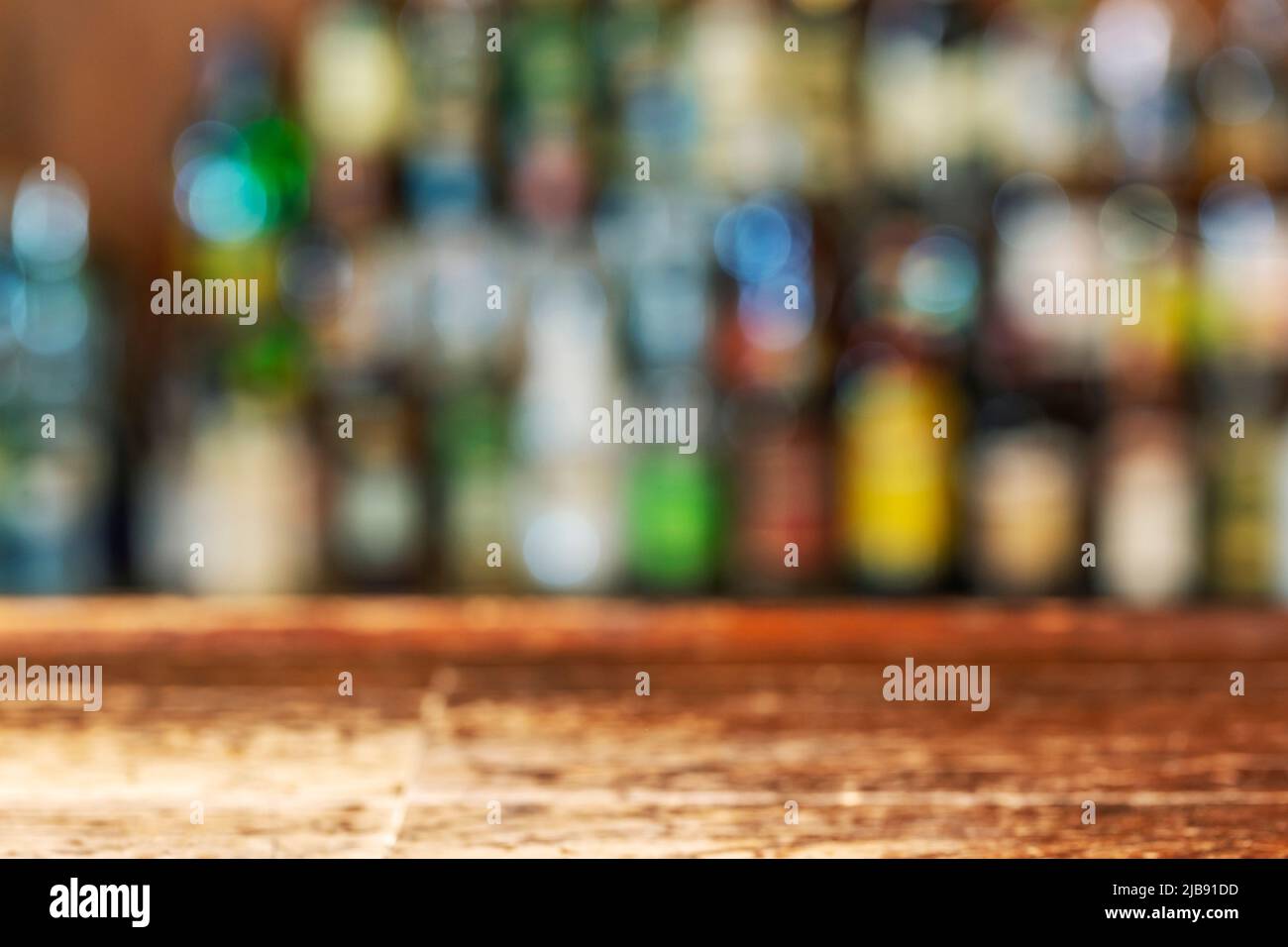 Empty wooden bar counter with defocused background and bottles of ...